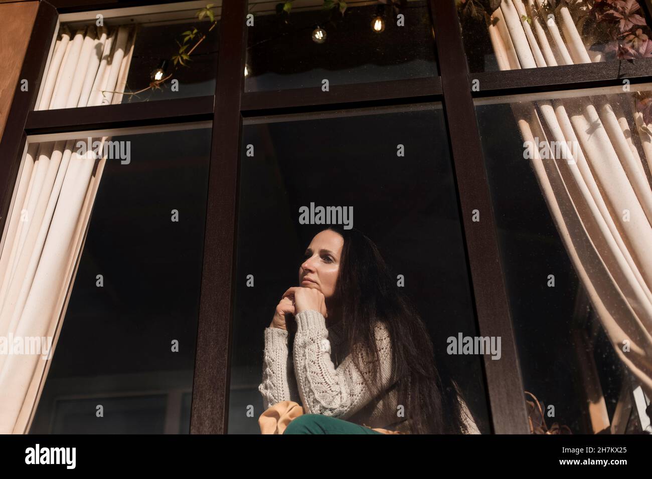 Woman with hand on chin looking out of window Stock Photo - Alamy