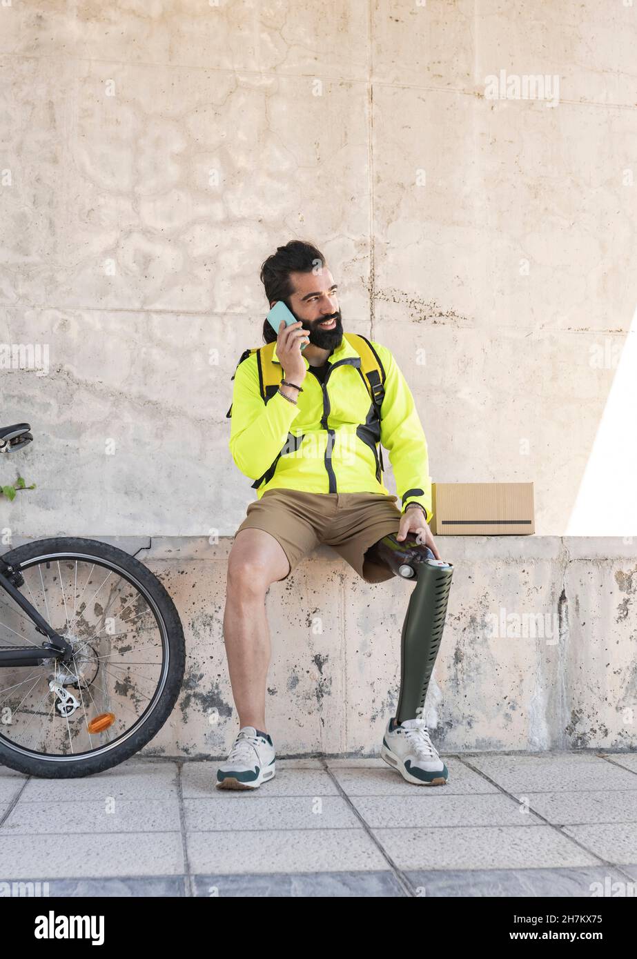 Disabled delivery man scanning box with smart phone in public park ...