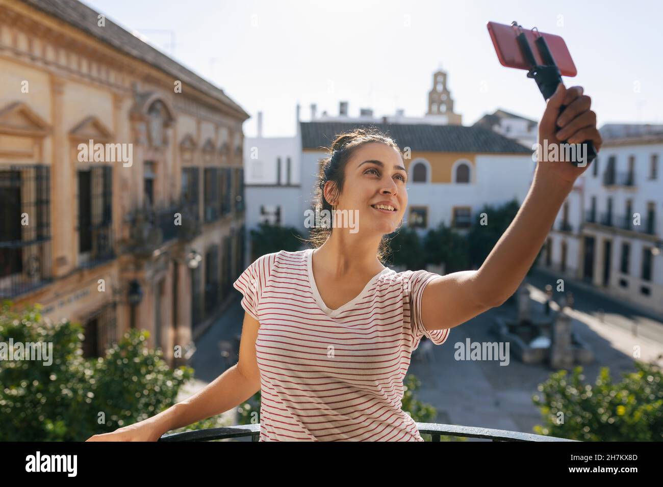 Smiling female influencer filming through mobile phone in balcony Stock ...