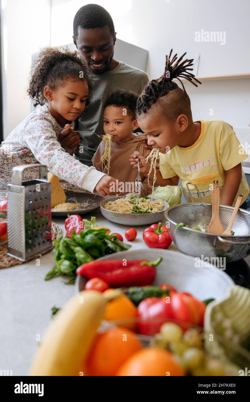 Family enjoying spaghetti in kitchen at home Stock Photo - Alamy
