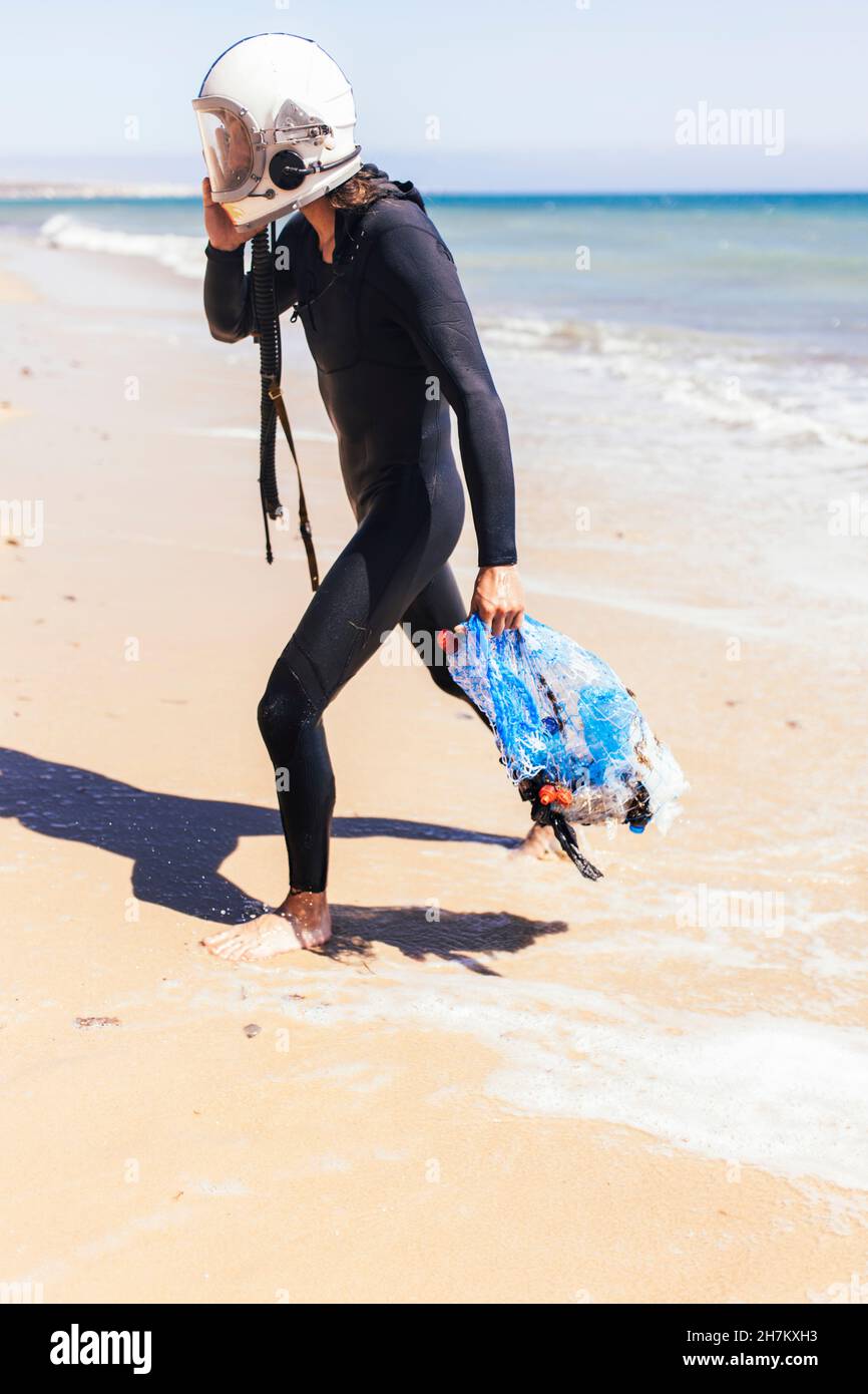 Male volunteer wearing helmet walking at beach Stock Photo - Alamy