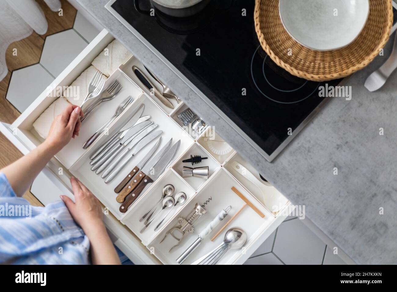 Top view closeup housewife hands tidying up cutlery in drawer general ...