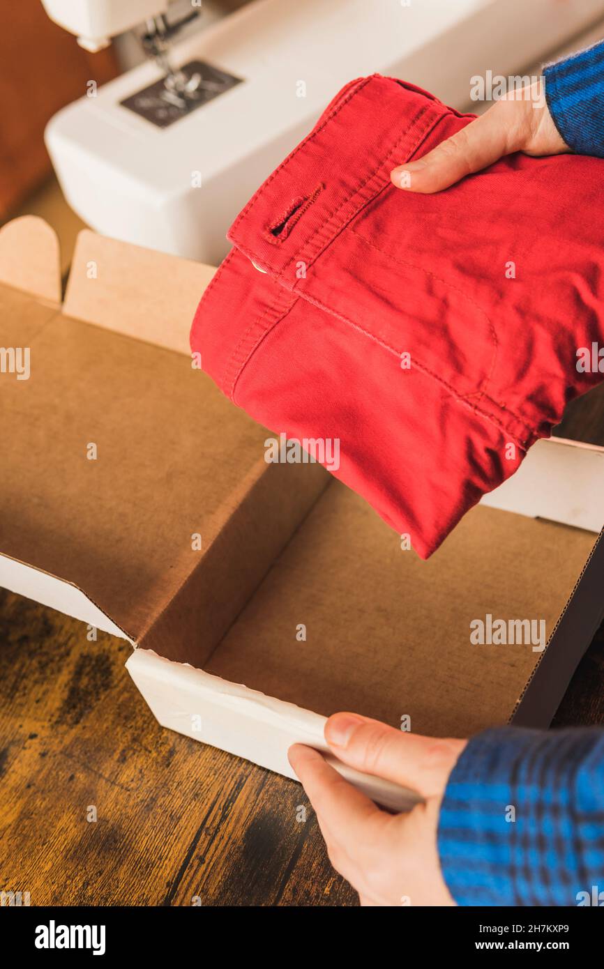 Female dressmaker putting clothes in cardboard box Stock Photo - Alamy