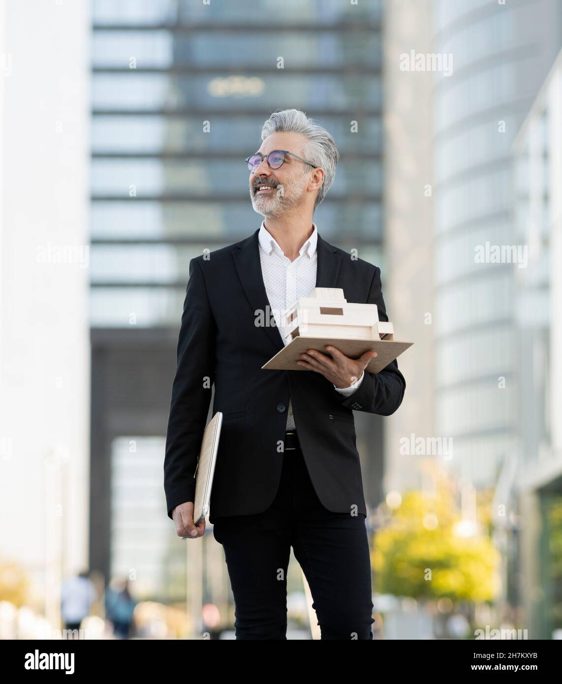 Architect walking holding house model outside office building Stock ...