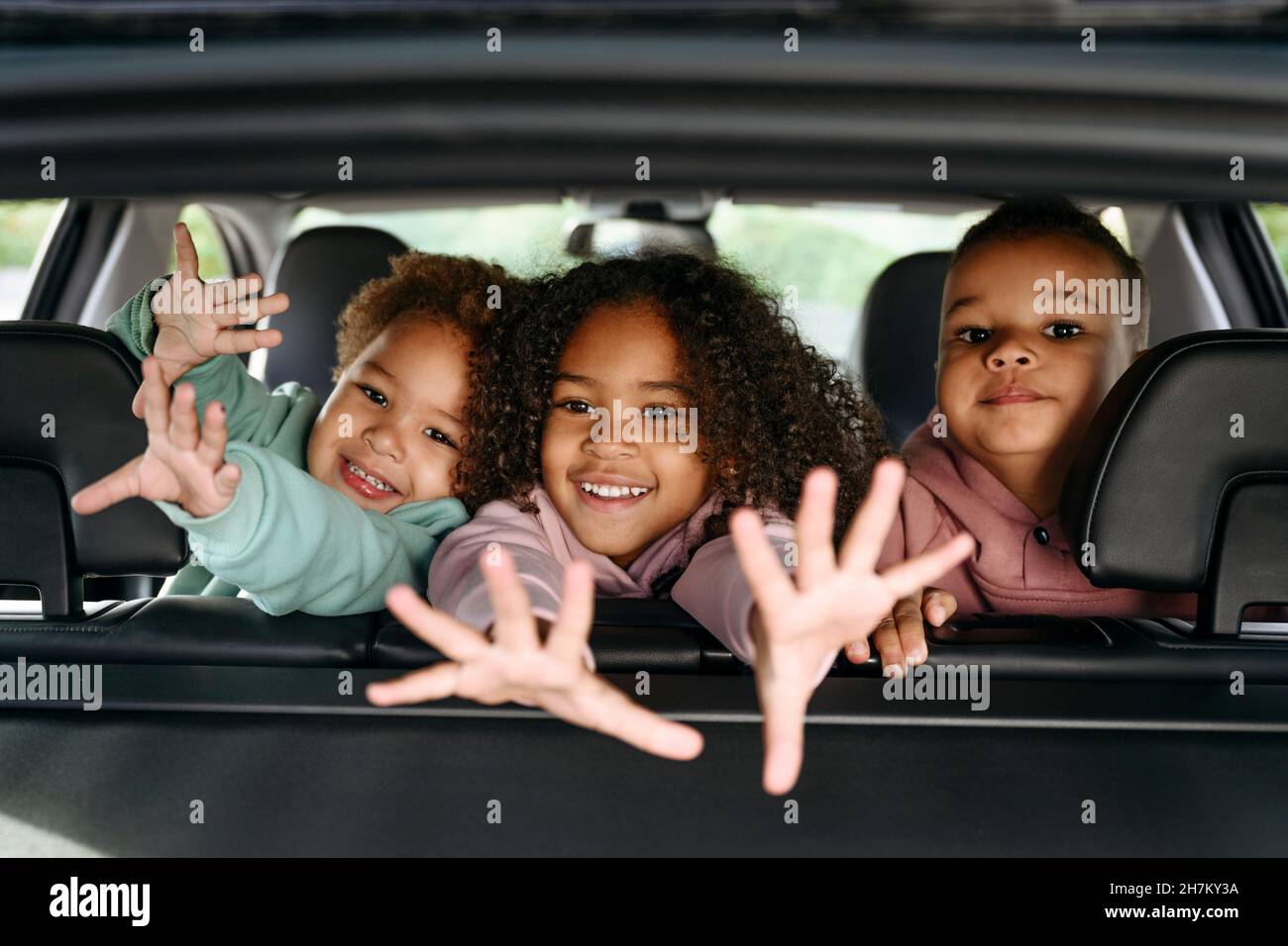 Smiling brothers and sister playing at car back seat Stock Photo - Alamy