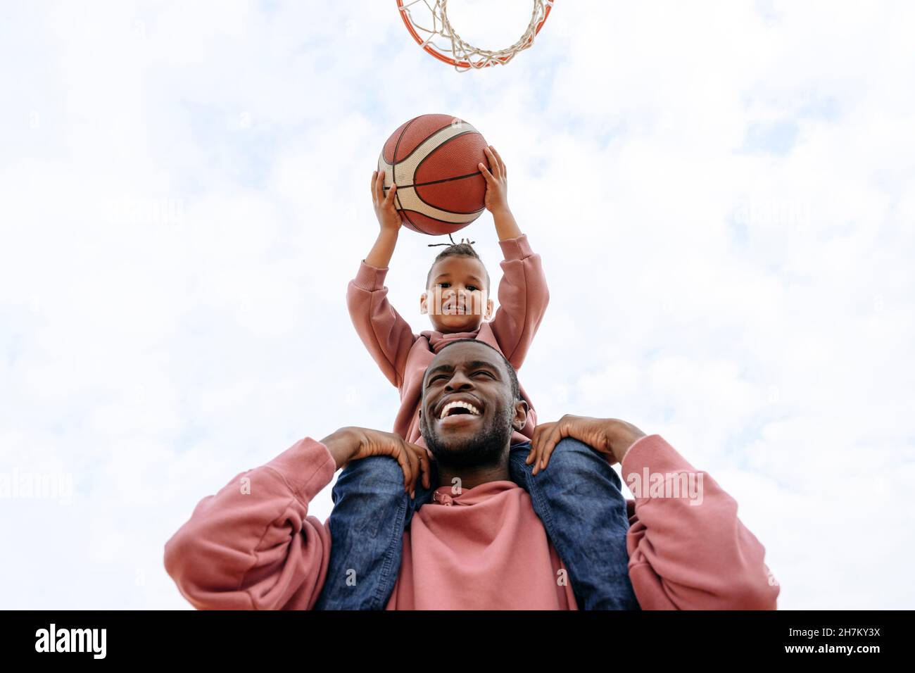 Cheerful father and son playing basketball at sports court Stock Photo ...