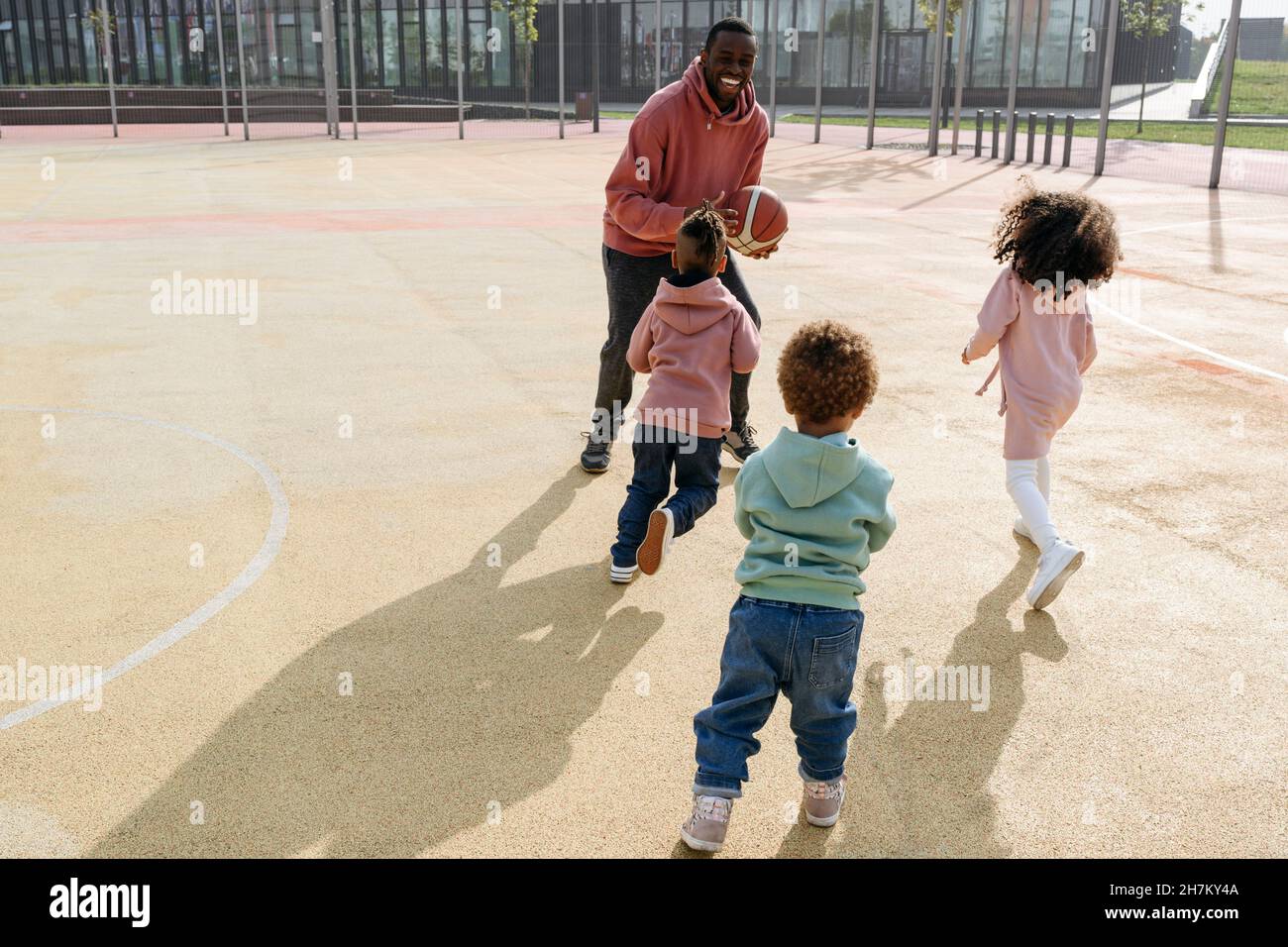 Cheerful father playing basketball with children on sports field Stock ...