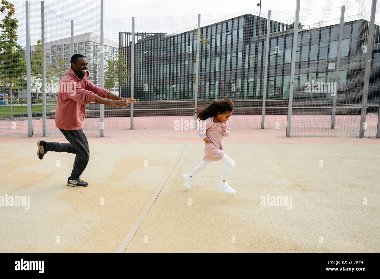 Smiling father catching daughter on sports field Stock Photo - Alamy