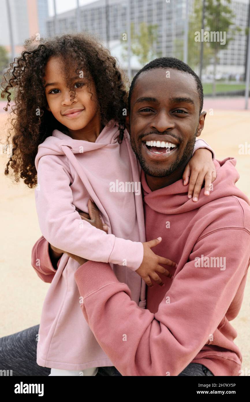 Smiling father hugging daughter at sports field Stock Photo - Alamy
