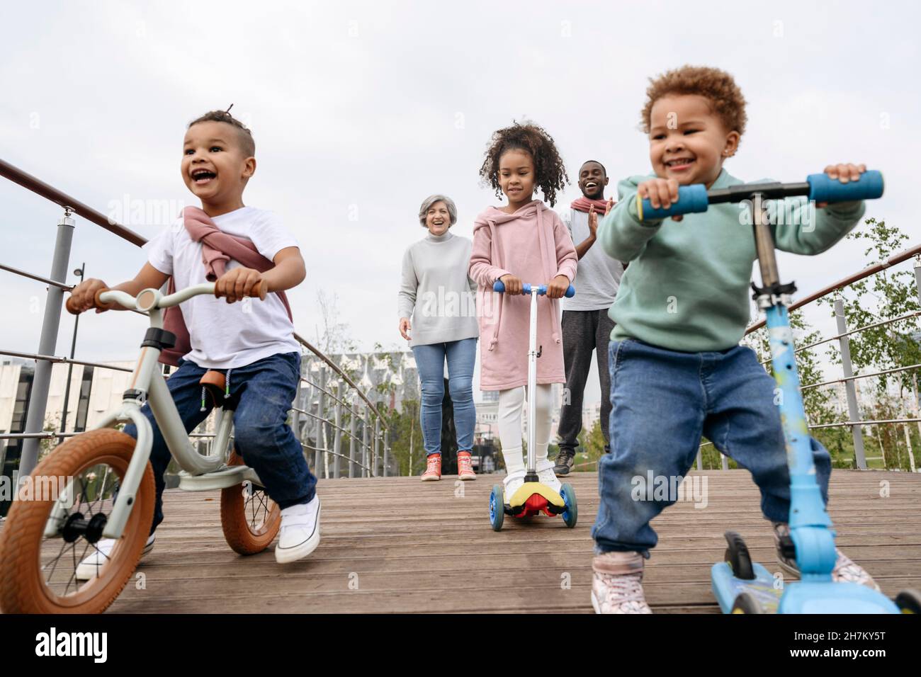 Happy children playing with push scooters and bicycle on bridge Stock ...