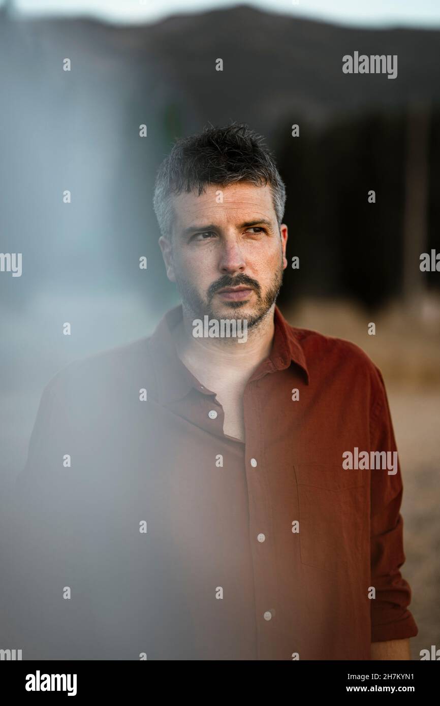 Serious man standing in field Stock Photo - Alamy