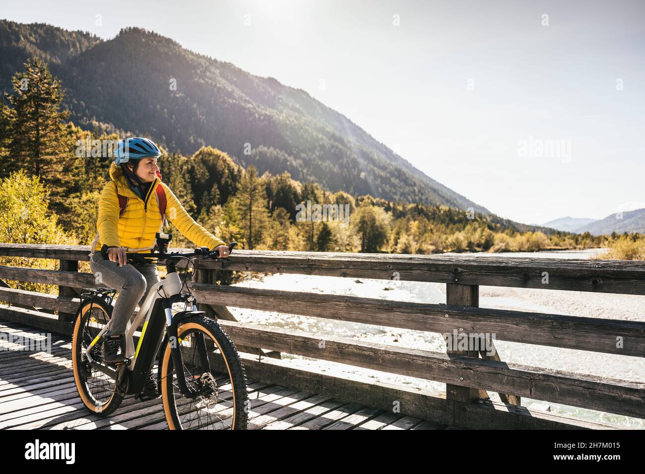 Woman with crash helmet cycling on bridge Stock Photo - Alamy