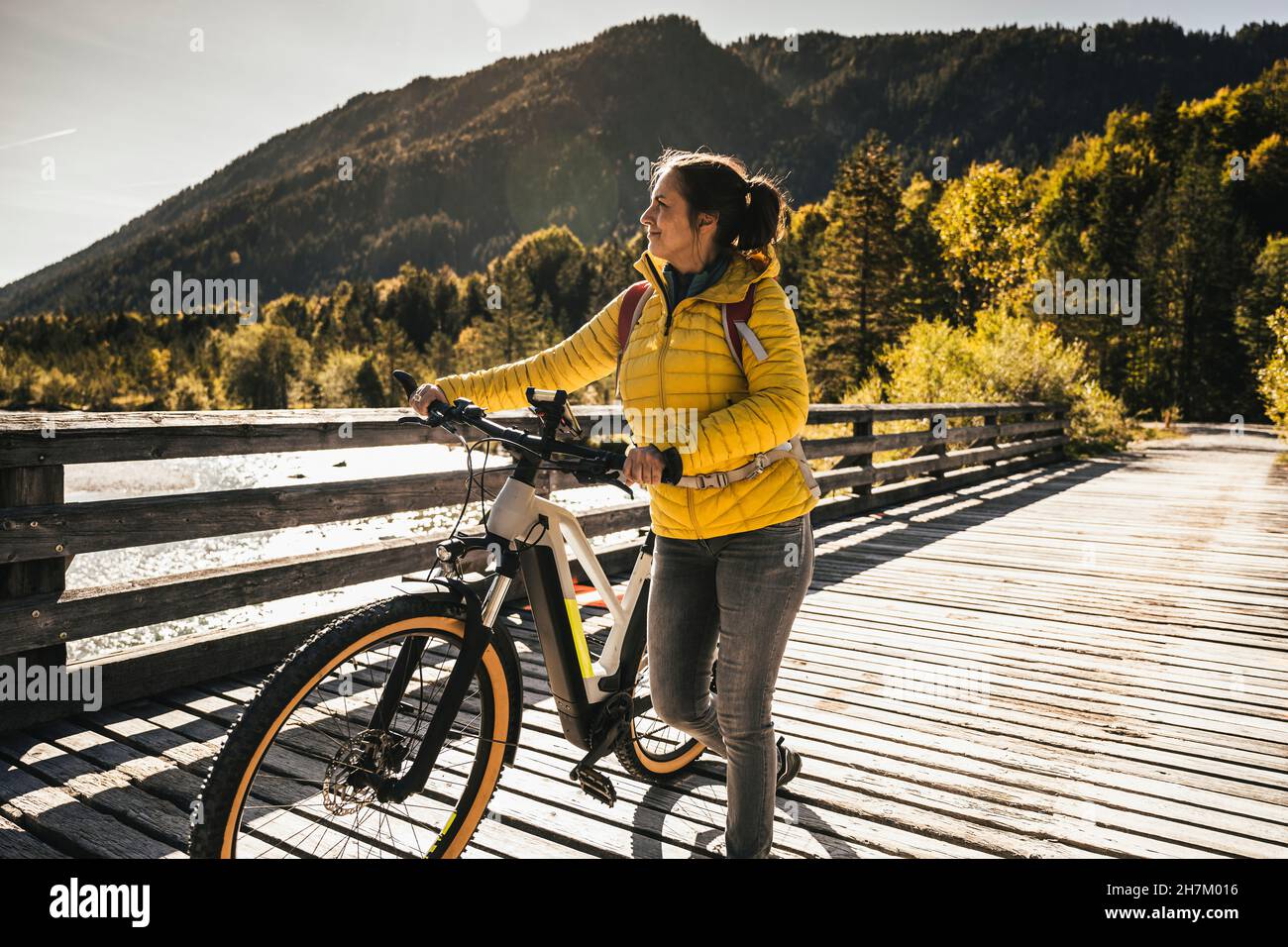 Smiling woman wheeling bicycle on bridge Stock Photo - Alamy