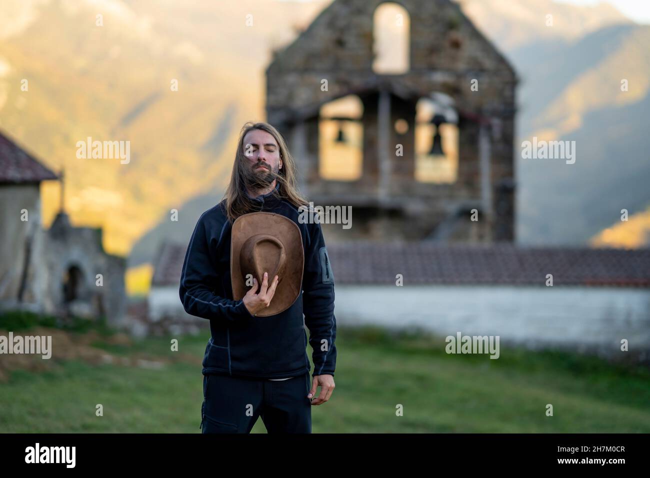 Bearded man with eyes closed holding hat at cemetery Stock Photo - Alamy