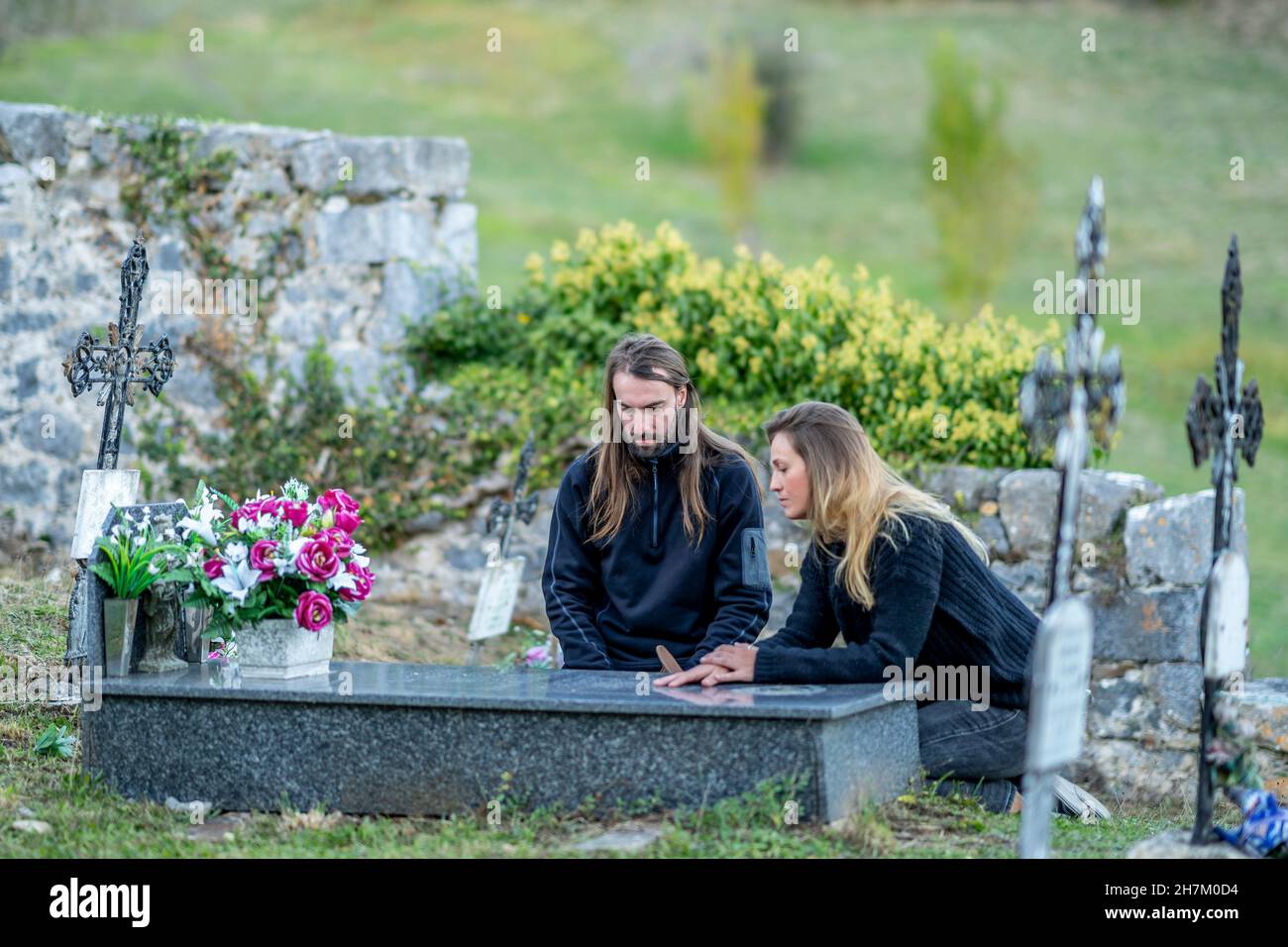 Woman consoling man at cemetery Stock Photo - Alamy