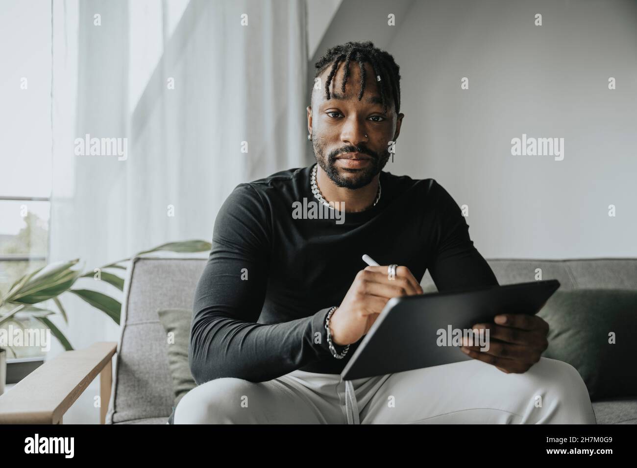 Man with hair locs holding tablet PC at home Stock Photo - Alamy