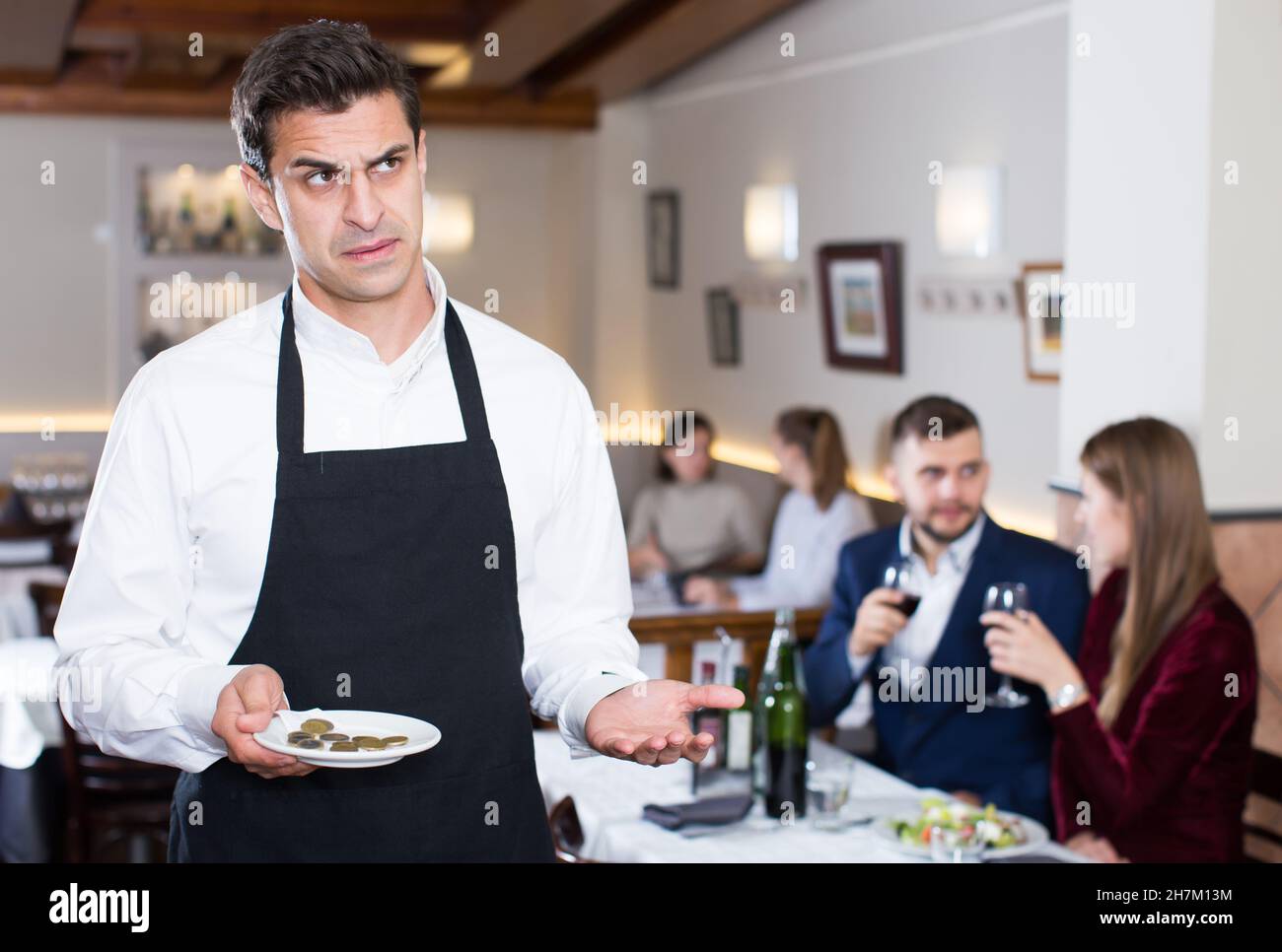 Man waiter dissatisfied with small tip from restaurant visitors Stock ...