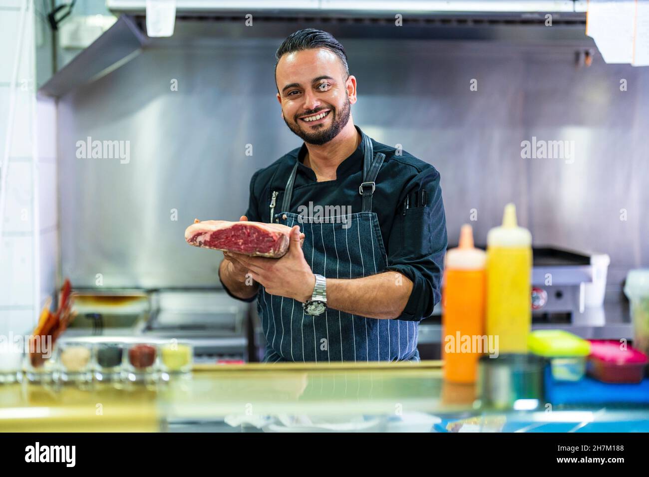 Smiling chef holding meat in kitchen of restaurant Stock Photo - Alamy