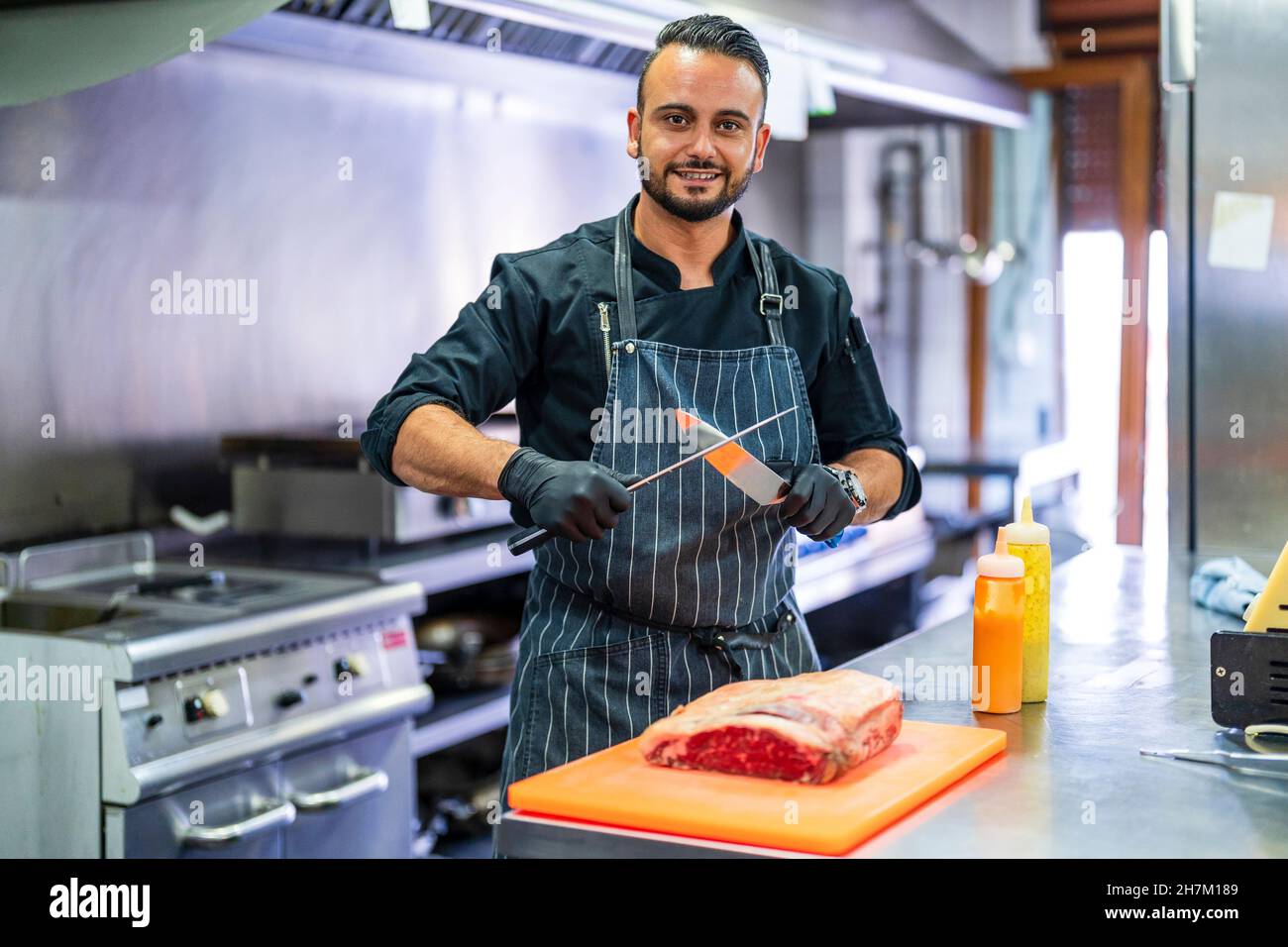 Chef sharpening knife for cutting meat in commercial kitchen Stock ...