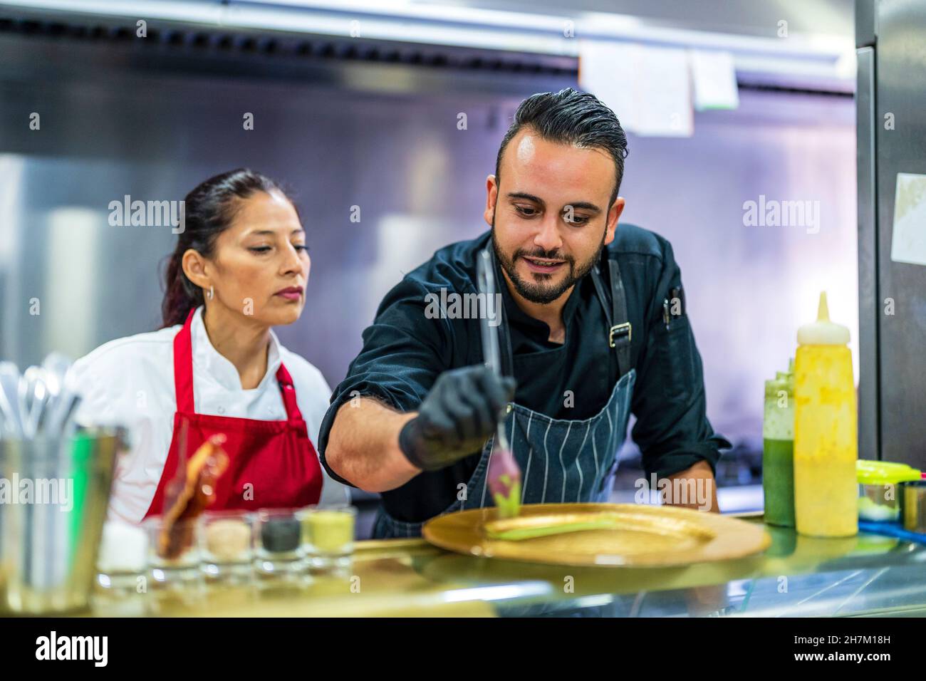Chef teaching plating to student in restaurant kitchen Stock Photo - Alamy