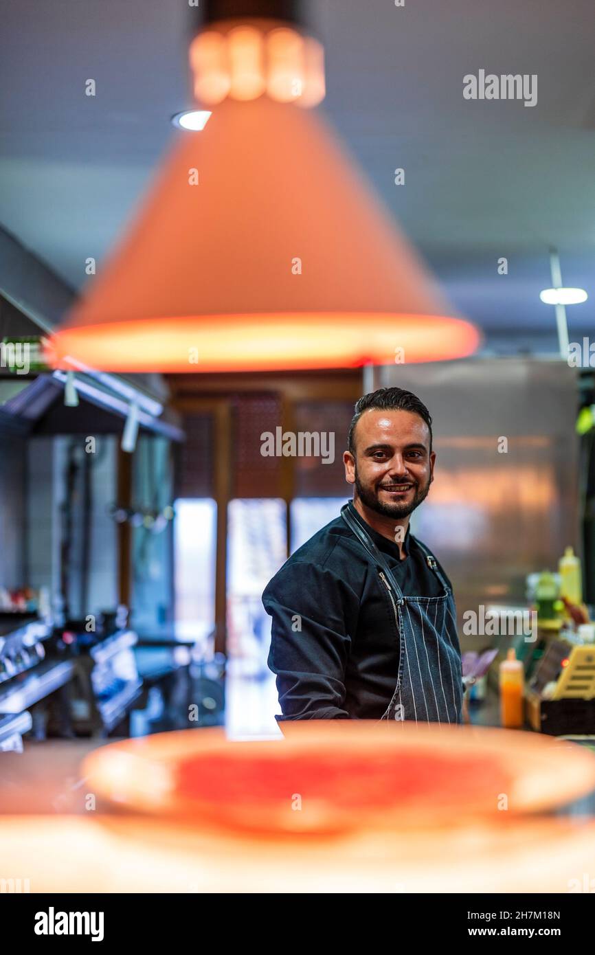 Chef wearing apron standing in commercial kitchen Stock Photo - Alamy