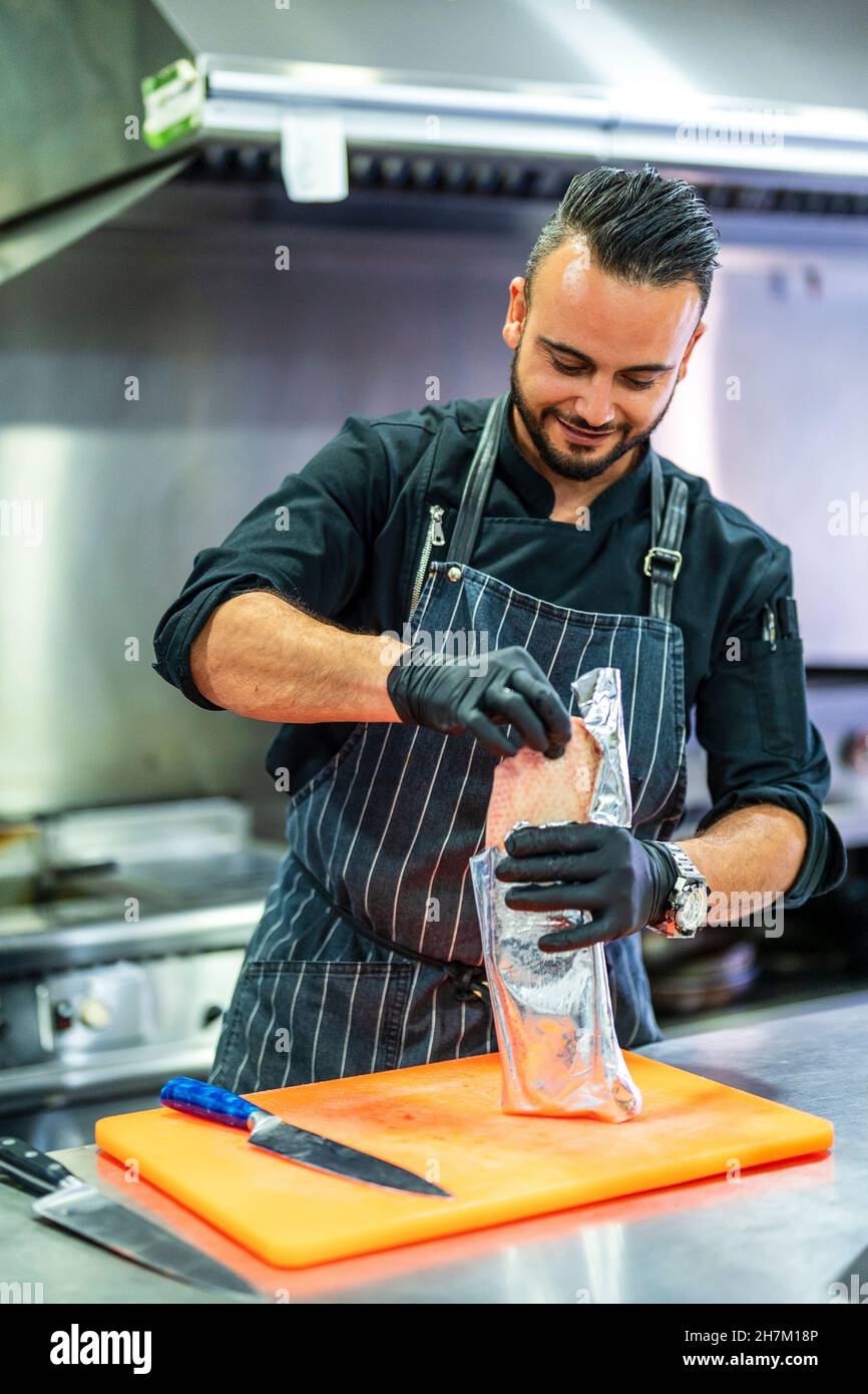 Chef opening food packet in restaurant kitchen Stock Photo - Alamy