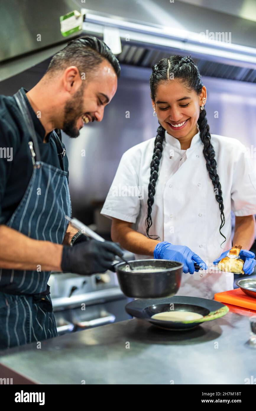 Smiling chef and trainee plating food in commercial kitchen Stock Photo ...