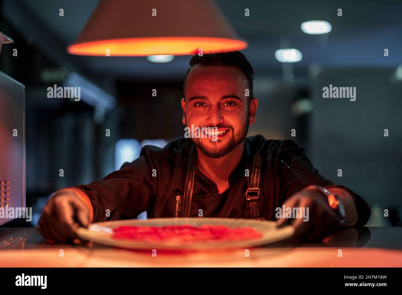 Chef keeping food plate below pendant light in restaurant kitchen Stock ...