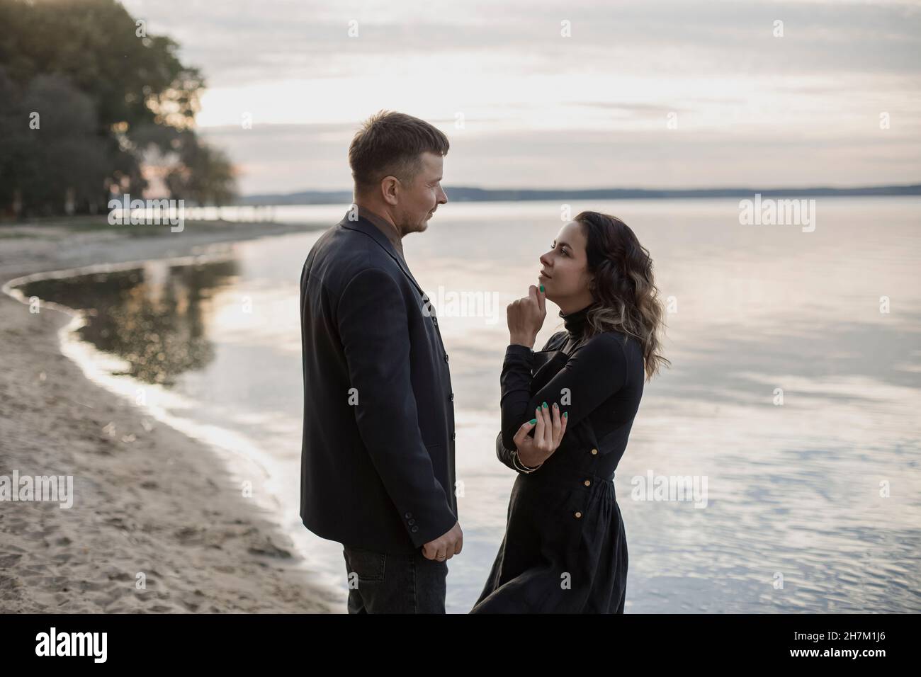 Woman with hand on chin staring at man standing near lakeshore Stock ...