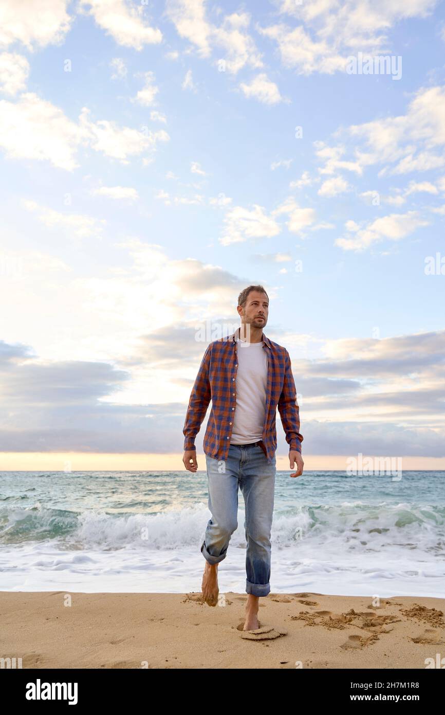 Man walking on sand at beach Stock Photo - Alamy