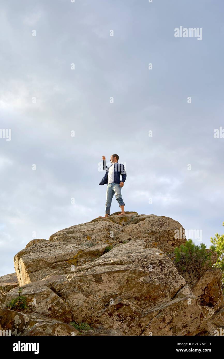 Man shielding eyes looking into sunset from top of rock at beach Stock ...