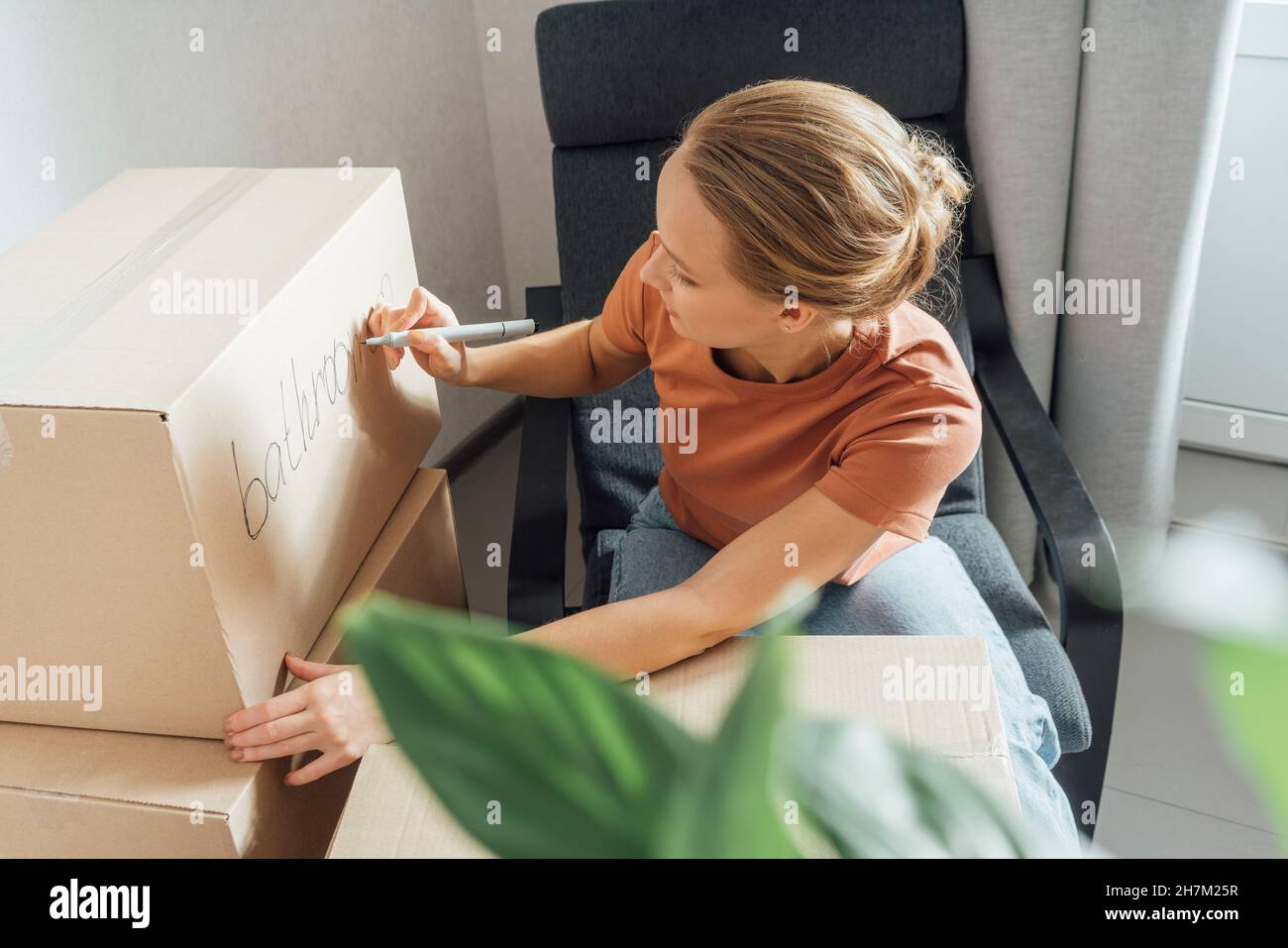 Woman writing on cardboard box in new apartment Stock Photo - Alamy
