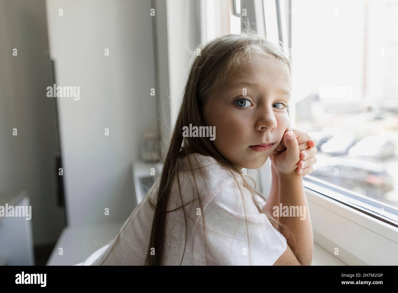 Girl leaning on window sill at home Stock Photo - Alamy