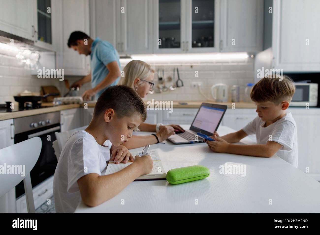 Mother cooking children studying in hi-res stock photography and images ...