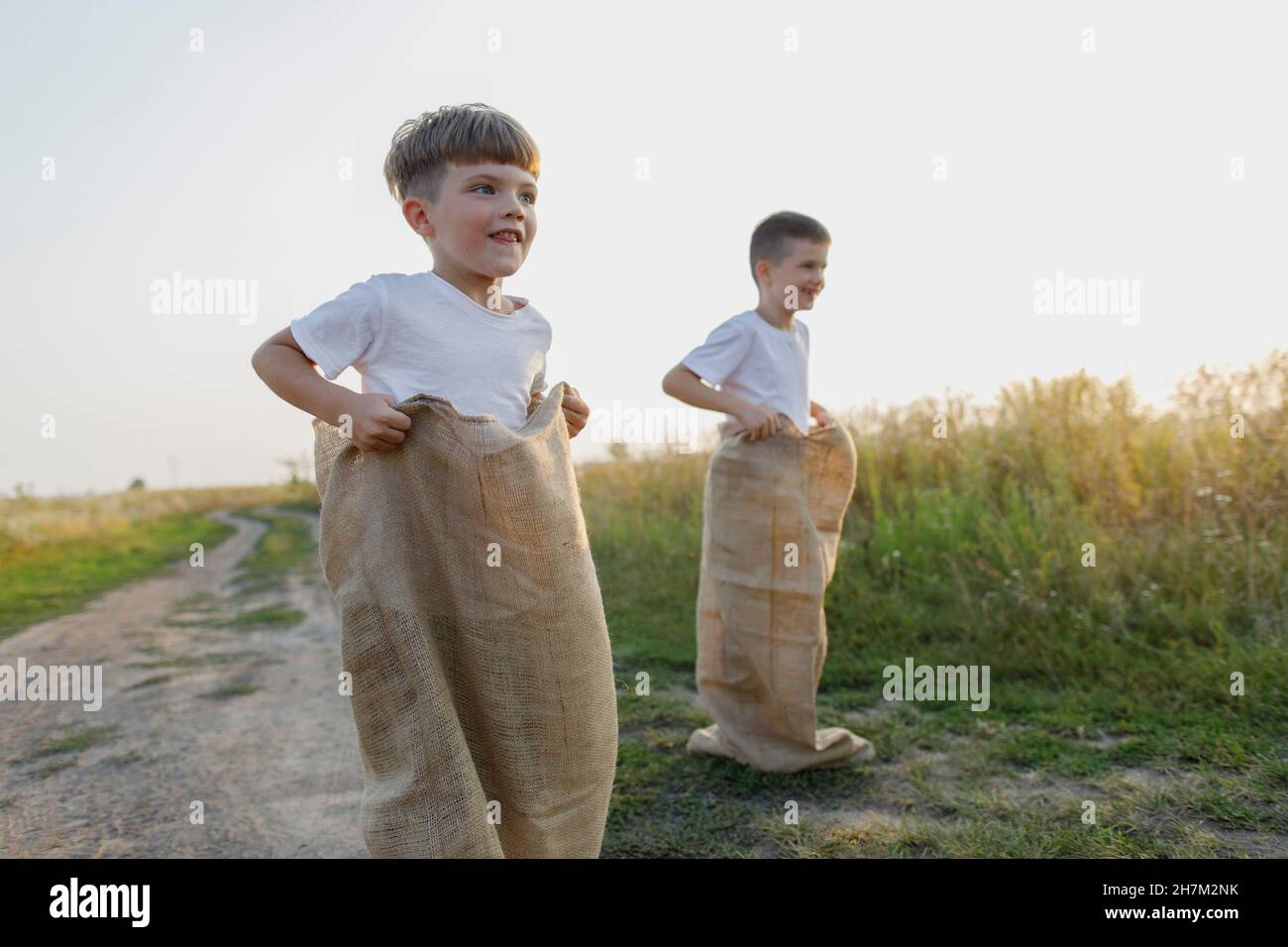 Siblings enjoying sack race at meadow Stock Photo - Alamy