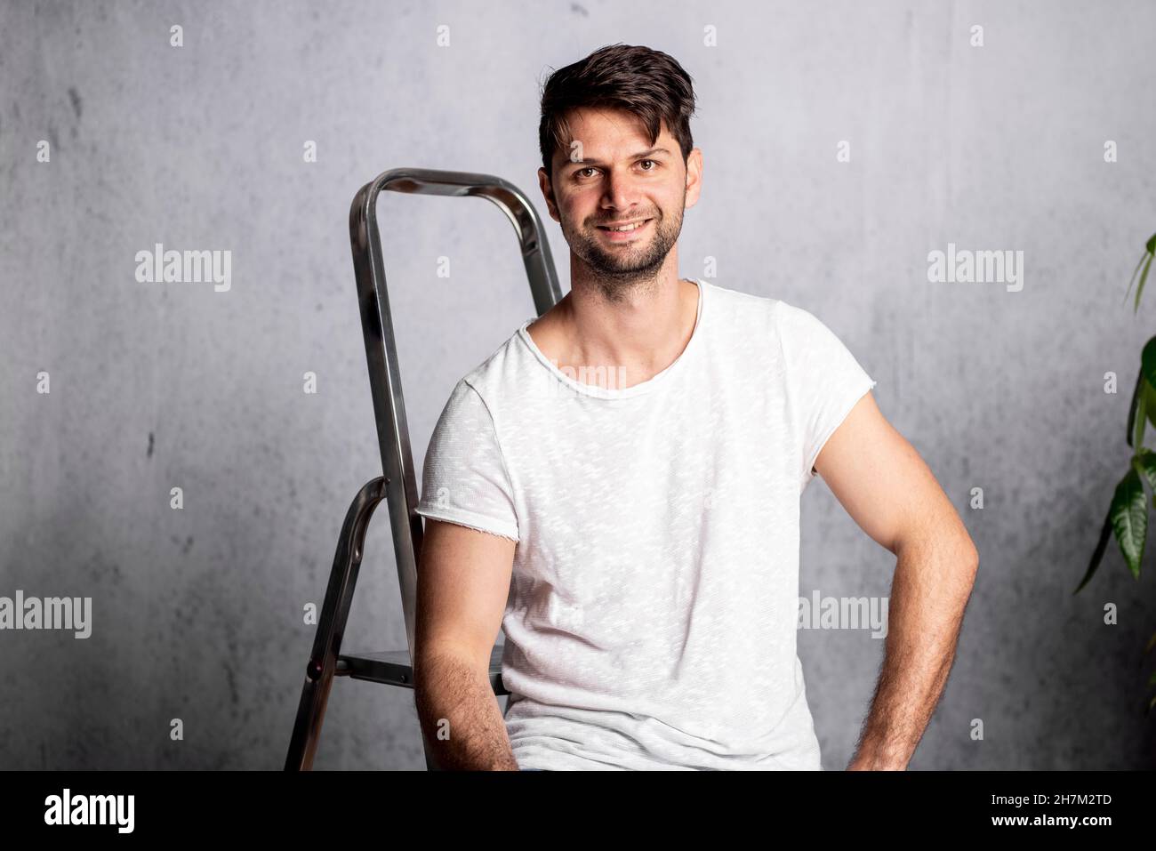 Smiling man with hair stubble sitting on ladder Stock Photo - Alamy