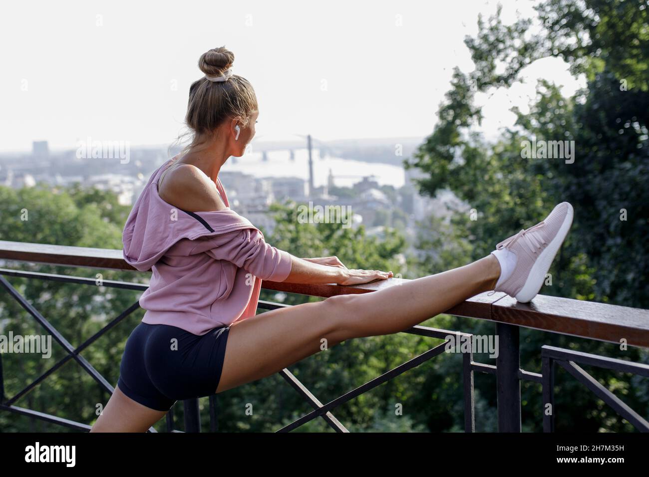 Flexible woman stretching legs on railing Stock Photo - Alamy