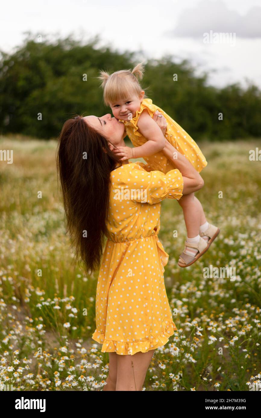 Mother holding aloft and kissing daughter on meadow Stock Photo - Alamy