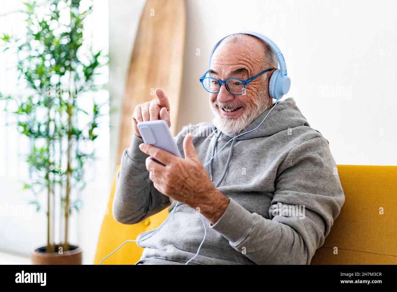 Man with headphones attending video call through mobile phone at home ...