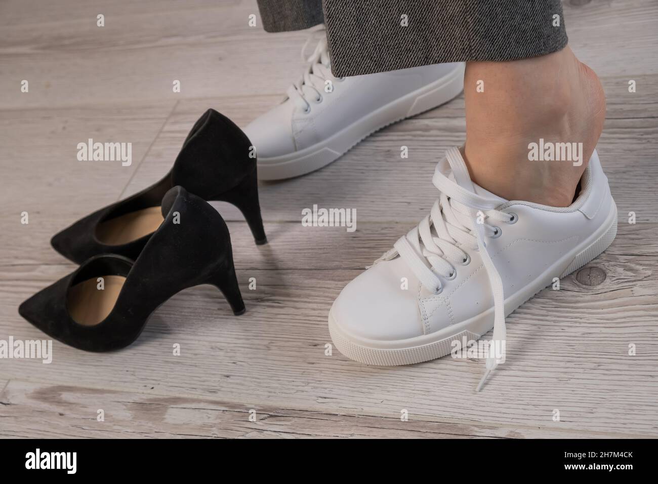 Close-up business woman takes off her shoes puts on white leather ...