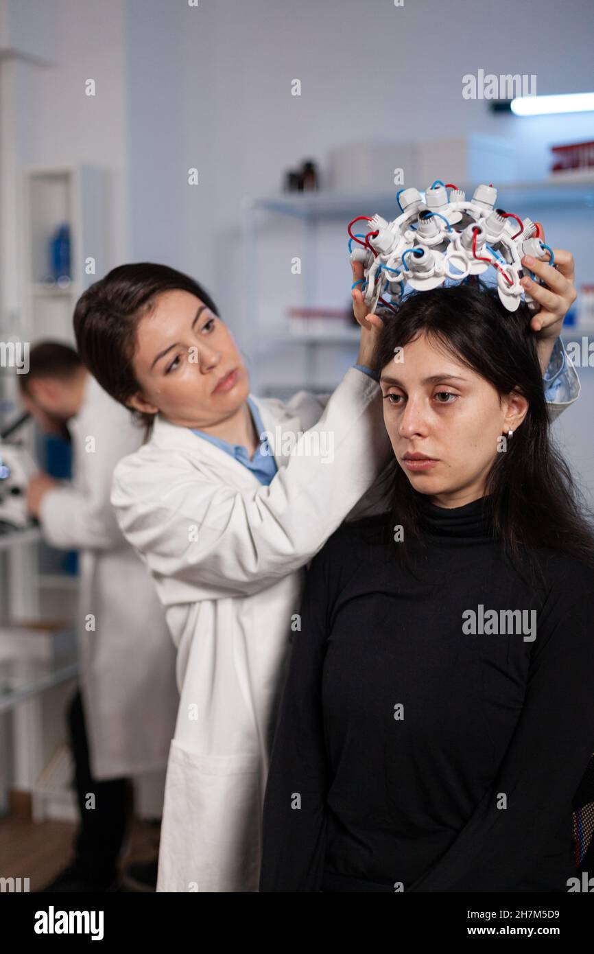 Researcher engineer woman putting eeg scanner on woman patient head ...
