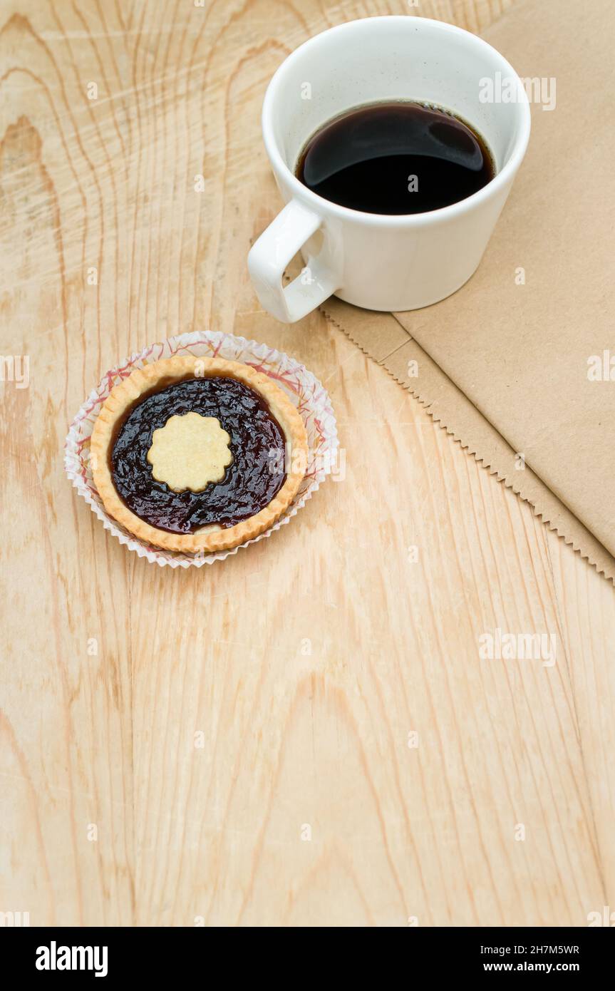 delicious jam short crust pastry and black coffee cup on a food paper ...
