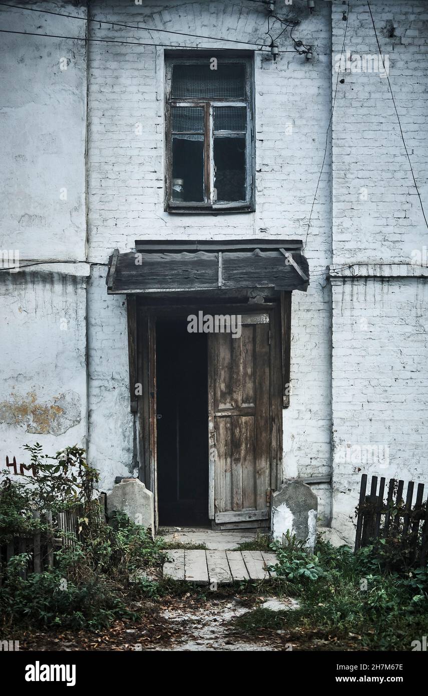 A doorway of an old run down house in a foggy laneway at dawn in a ...