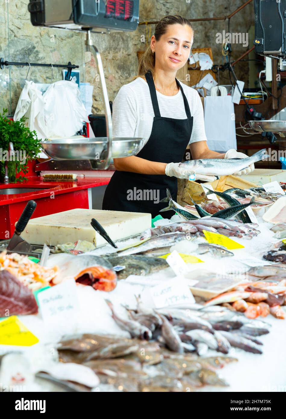Female fishmonger offering sea bass Stock Photo - Alamy