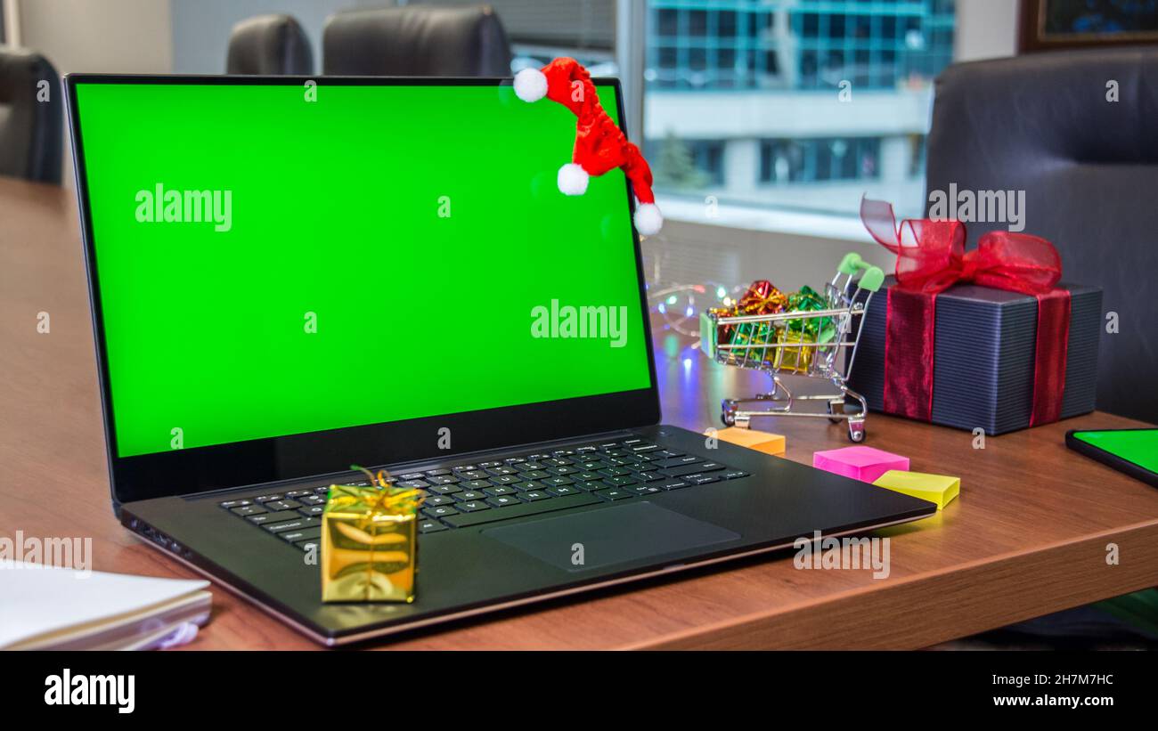 Laptop with green screen mockup, shopping cart full of gifts on ...