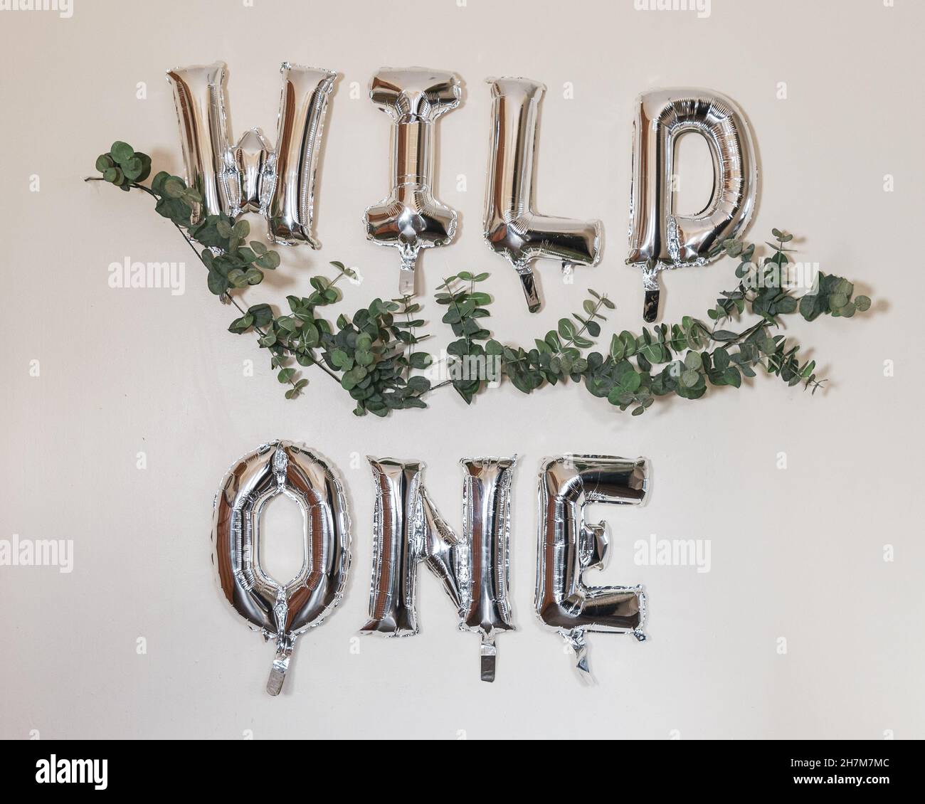Decoration with silver letter balloons saying 'wild one' on a beige ...
