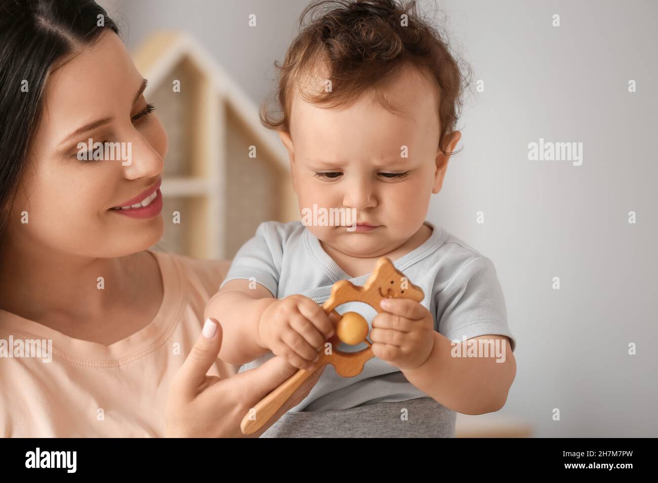 Young mother holding cute little baby with rattle at home Stock Photo - Alamy
