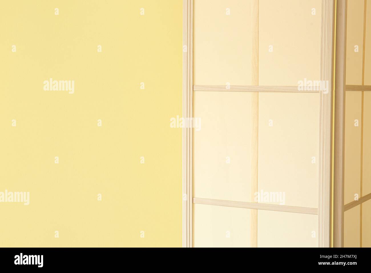 Modern beige folding screen near yellow wall Stock Photo - Alamy