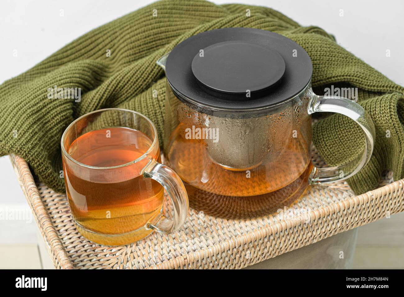 Tray with tea pot and glass cup of hot beverage on table near blue wall ...
