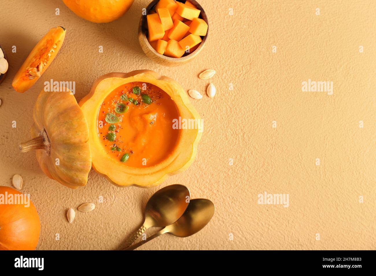 Tasty cream soup served in pumpkin and seeds on color background Stock ...